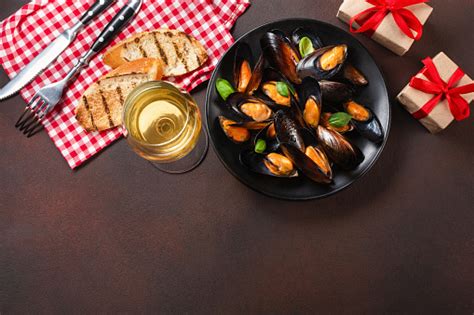 수건과 녹슨 배경에 와인 잔 포크 칼 선물 상자가 있는 검은 접시에 해산물 홍합과 바질 잎 끓는 물에 삶기에 대한 스톡 사진 및 기타 이미지 Istock