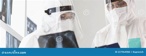 два врача в защитных костюмах и масках исследуют рентген Стоковое Фото