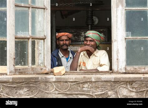 Two Workers Looking Out Of The Window At The Kolukkumalai Tea Factory