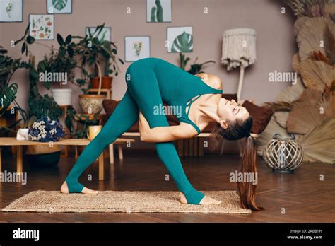 Young Sporty Woman Practicing Yoga At Home Doing Revolved Triangle Pose