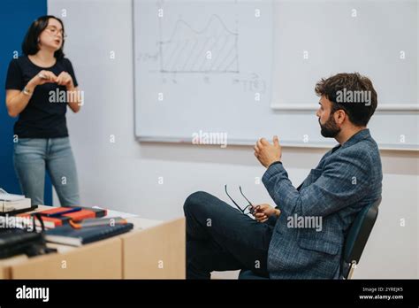 Student Presenting Data Analysis To Teacher In Classroom Setting Stock