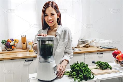 健康的女性喜欢在家厨房用搅拌器制作绿色蔬菜排毒和绿色水果奶昔。节食的概念。健康的生活方式素材 花瓣网