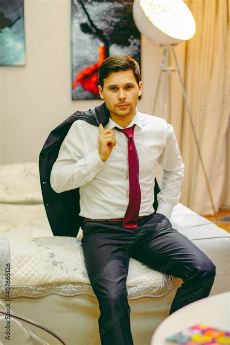 Man In Suit And Red Tie Sitting On The Edge Of The Bed Man In Suit In