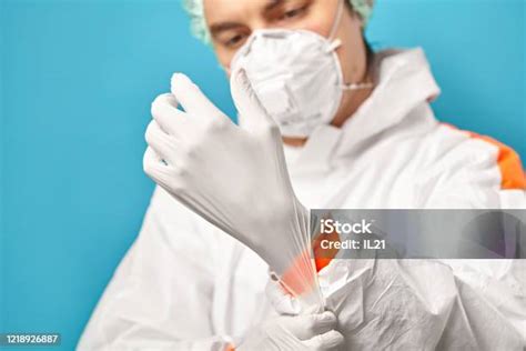 평범한 파란색 배경 위에 멸균 장갑을 착용하는 보호 복을 입은 의사의 클로즈업 의료 절차 중 환경 친화성 및 안전 Stem
