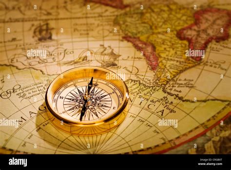 An Antique Gold Compass Set Upon A Sixteenth Century Map Of The World