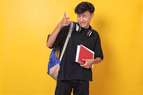 Premium Photo Asian Male Student Carrying Backpack And Books Pointing