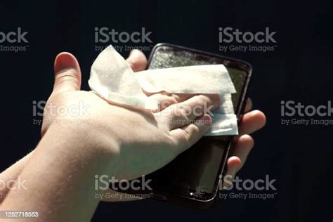 여자는 전화를 소독합니다 소독제 살균 여자의 손은 휴대 전화에 천으로 닦아 세균이나 박테리아의 감염을 방지 스마트 폰을 청소