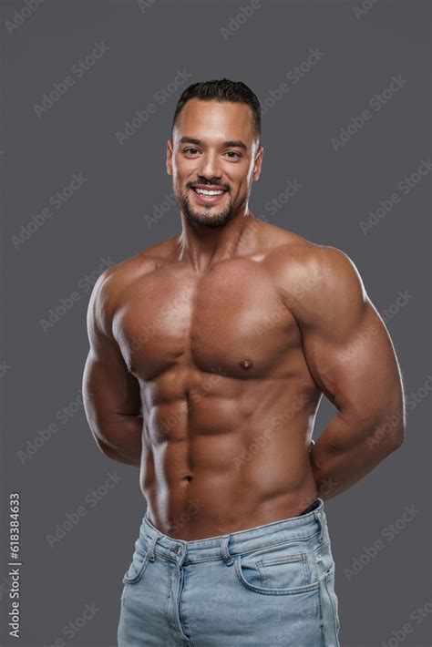Charming And Muscular Male Model With A Dazzling Smile Poses Shirtless