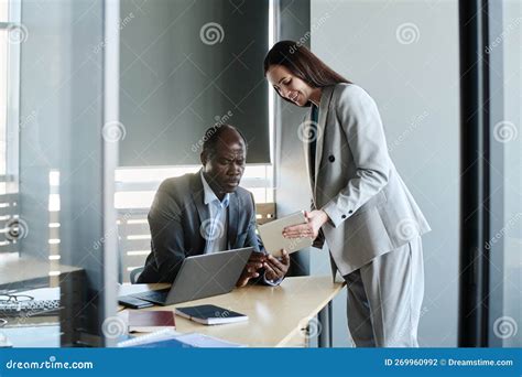 Happy Young Secretary With Tablet Bending Over Workplace Of Her Boss