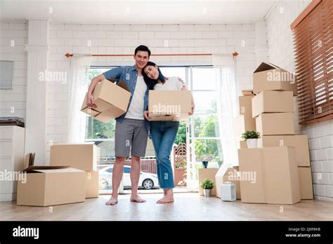 Joyeux jeune couple transportant des boîtes en carton et debout dans la