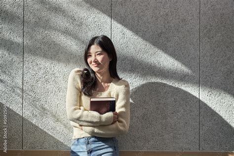 아시아 한국의 빛이 들어오는 대학교 강의실 벽에 기대어 있는 젊은 여자 대학생 모델 Stock 사진 Adobe Stock