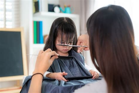 Asiatische Mutter Schneidet Ihrer Tochter Im Wohnzimmer Zu Hause Haare W Hrend Sie W Hrend Der
