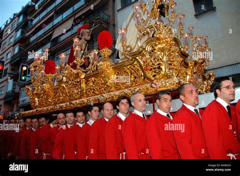 Men In Red Cassocks Carry Heavy Religious Throne Float Through Malaga