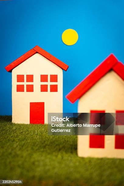 푸른 잔디밭에 빨간 지붕이 달린 미니어처 장난감 집 머리 위로 빛나는 노란 태양은 가정의 화합과 가족의 따뜻함을 상징합니다 0명에 대한 스톡 사진 및 기타 이미지 Istock