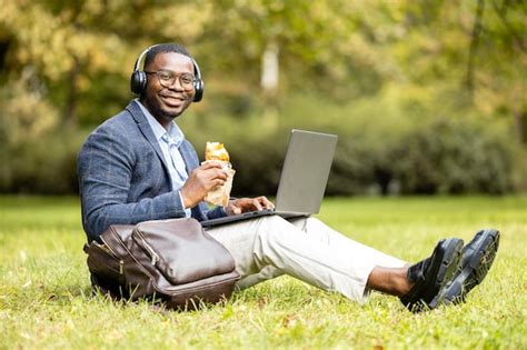 Premium Photo Businessman Sitting On Grass In The Park Eating His