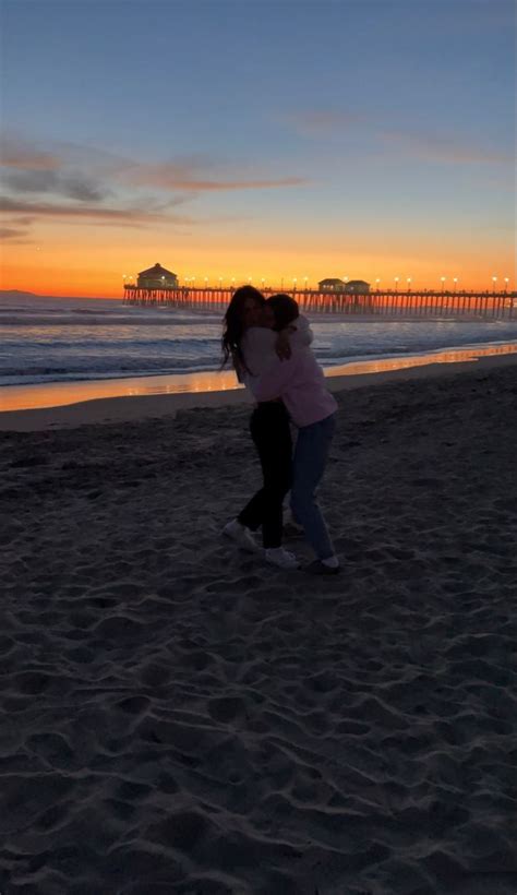 Two People Kissing On The Beach At Sunset