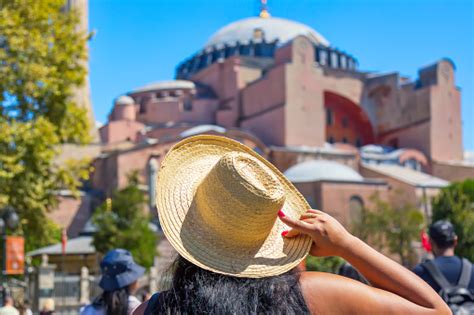 관광 개념입니다 밀짚모자를 쓴 한 여성이 튀르키예 이스탄불의 술탄아흐메트 지구에 있는 아야 소피아 그랜드 모스크를 바라보고 있다 후방 View Byzantine에 대한 스톡