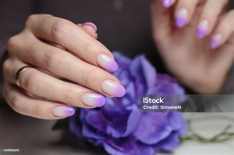 보라색 손톱 디자인을 가진 여성 손 클로즈업 그라데이션 바이올렛 글리터 매니큐어를 사용한 예술적 매니큐어 가꿔주기에 대한 스톡