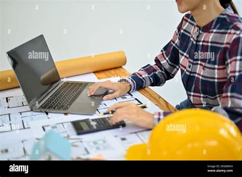 A Female Architect Or Engineer Working At Her Desk Using Scientific Calculator And Laptop