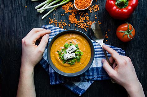 신선한 야채와 허브로 장식 된 붉은 렌즈 콩 크림 수프 한 남자가 수프를 먹는다 채식 개념입니다 적절한 영양 0명에 대한 스톡