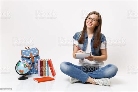 글로브 책 가방 학교 책 흰색 배경에 고립 근처에 앉아 노트북에 메모를 작성 하는 안경에 젊은 즐거운 아름 다운 여자 학생 고등