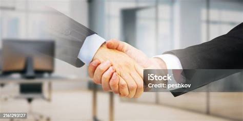 Two People Shaking Hands In An Office Setting With A Handshake Graphic