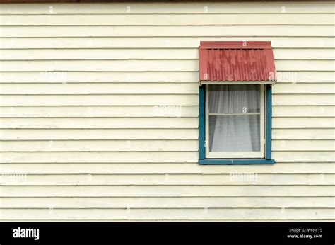 The Side Of A Cream Painted Timber Cottage With A Small Single Double