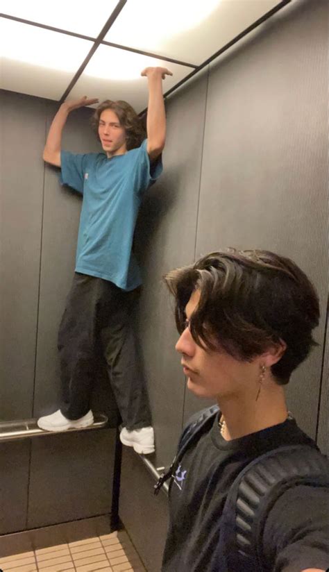 Two Young Men Standing In A Bathroom Next To Each Other With Their