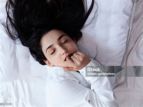 침대에 누워 있는 아름다운 여자 검은 머리 여자 포즈 와 그녀의 손가락 에 입 여자 즐기는 물린 손가락 행복 레크리에이션 만족과 즐거움을 느낌 25 29세에 대한 스톡 사진