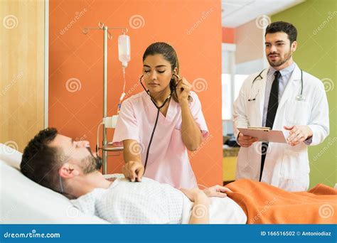 Médico De Sexo Masculino Y Femenino Que Atiende A Pacientes Hospitalizados Foto De Archivo