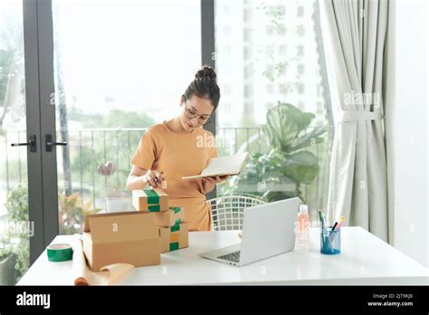 Woman Checking Purchase Order In Laptop And Write In The Delivery On Package Box Sell Online