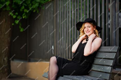 Free Photo Blonde Woman On Black Dress Necklaces And Hat Sitting On Bench