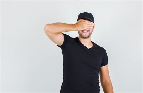 Free Photo Delivery Man Covering Eyes With Hand In Black T Shirt Cap