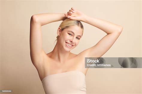 베이지색 배경에 깨끗하고 위생적인 겨드랑이 또는 겨드랑이를 과시하기 위해 손을 들어 올리는 아름다운 젊은 여성 부드러운 겨드랑이 청결 및 보호 개념 아름다움에 대한 스톡