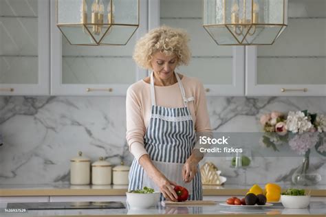 앞치마를 자르는 노인 여성은 빨간 파프리카를 자르고 채식 샐러드를 준비합니다 60 64세에 대한 스톡 사진 및 기타 이미지 60 64세 가정 주방 가정의 방 Istock