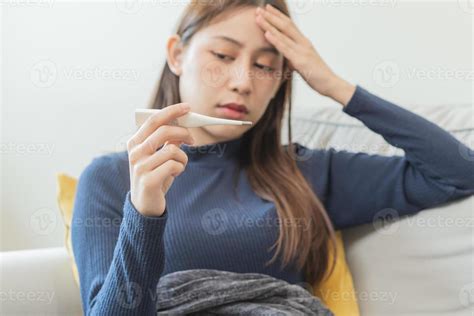 enfermo influenza asiático joven mujer niña mano en cheque dolor de cabeza tener un fiebre