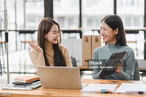 두 명의 여성이 현대적인 오피스 업무공간에서 활발한 토론을 벌이며 협업과 창의성을 선보였습니다 그들은 노트북과 문서에 둘러싸여 미소를 지으며 아이디어를 공유하고 있습니다