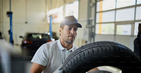 작업장에서 작업하는 동안 랙에 자동차 타이어를 쌓는 자동차 수리공 사진 Unsplash의 세르비아 이미지