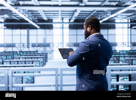 Employee In Server Hub Using Tablet To Monitor Energy Consumption