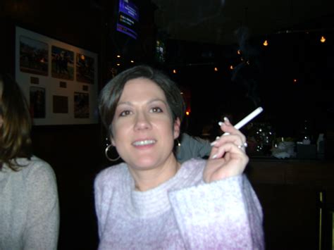 Mistress Gigi Smoking A Cigarette In A Bar Wearing Her Long Leather