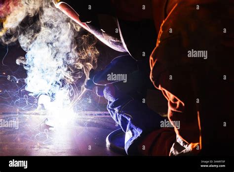 A Welder In A Welding Mask And Gloves Welds With Electric Arc Welding