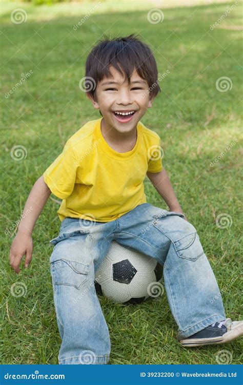 Милый мальчик сидя на футболе на парке Стоковое Фото изображение насчитывающей мило взгляд