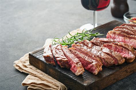 스테이크 얇게 썬 구운 고기 스테이크 뉴욕 또는 Ribeye는 오래된 나무 배경에 검은 대리석 보드에 향신료 로즈마리와 후추를