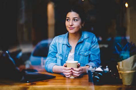 매력적인 재능 있는 여성 사진 작가 나무 테이블에 앉아 노트북에 유용한 응용 프로그램을 설치 하는 동안 숙고 귀여운 Hipster 여자 음료와 현대 장치 실내에서 시간을