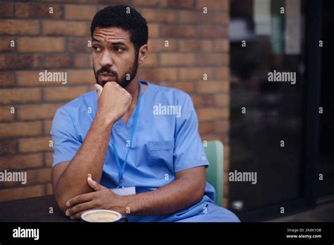 Unhappy Caregiver Man Resting Outdoor In Front Of Nurishing Home Stock