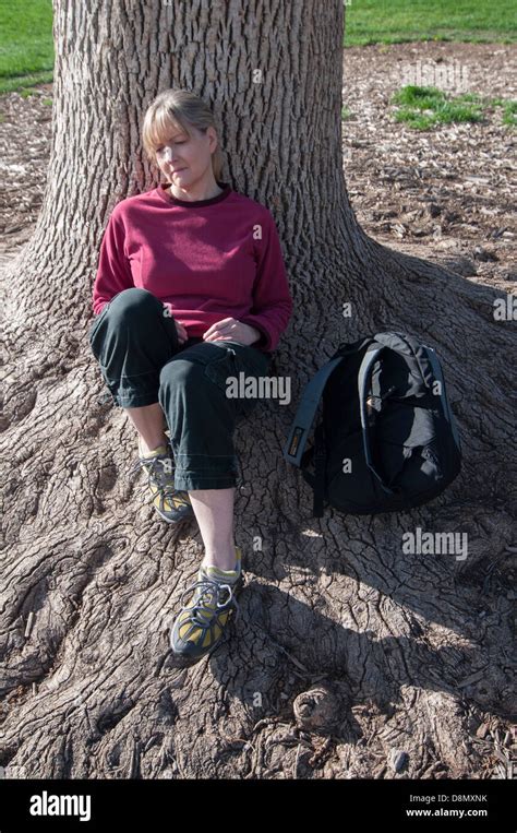 Woman Sitting On A Tree S Above Ground Roots Stock Photo Alamy