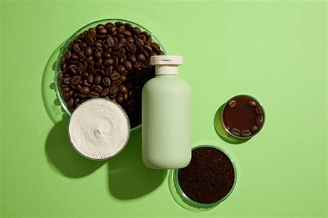 녹색 배경에 페트리 접시 용기 커피 콩 커피 찌꺼기 및 크림 질감에 표시된 녹색 병 광고용 모형 장면 스킨케어를 위한 천연 성분