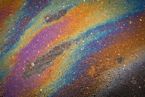 oil stains from leaks in the car engine oil after rain makes spots with rainbow reflections