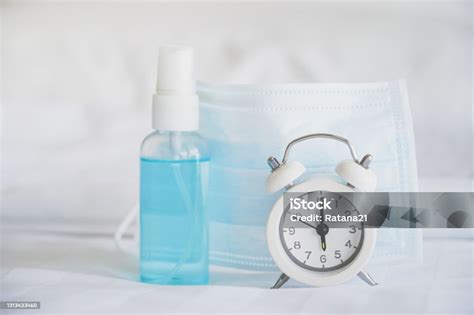화이트 아날로그 시계 흐린 알코올 스프레이 병 및 침대에 의료 마스크 코로나 바이러스 때문에 잠금 을 느슨하게 한 후 새로운