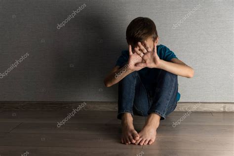 El chico asustado está cerrando la cabeza y la cara con las manos